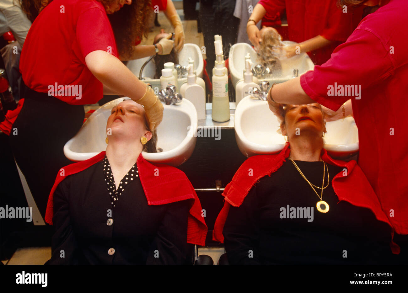 Businesswomen having shampoo sit side-by-side with both their heads ...