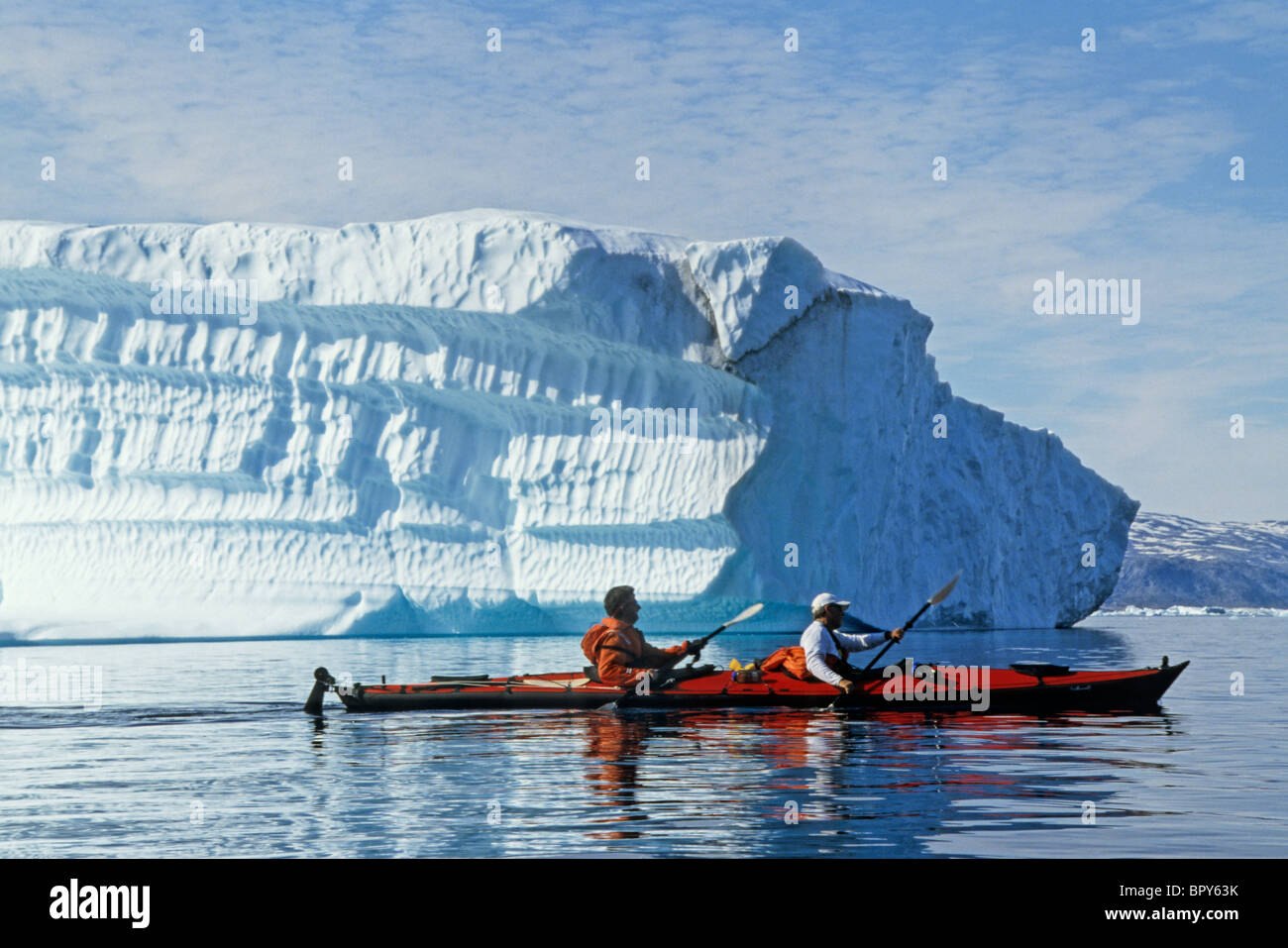 Sea kayakers paddling a tandem kayak pass an iceberg Stock Photo - Alamy