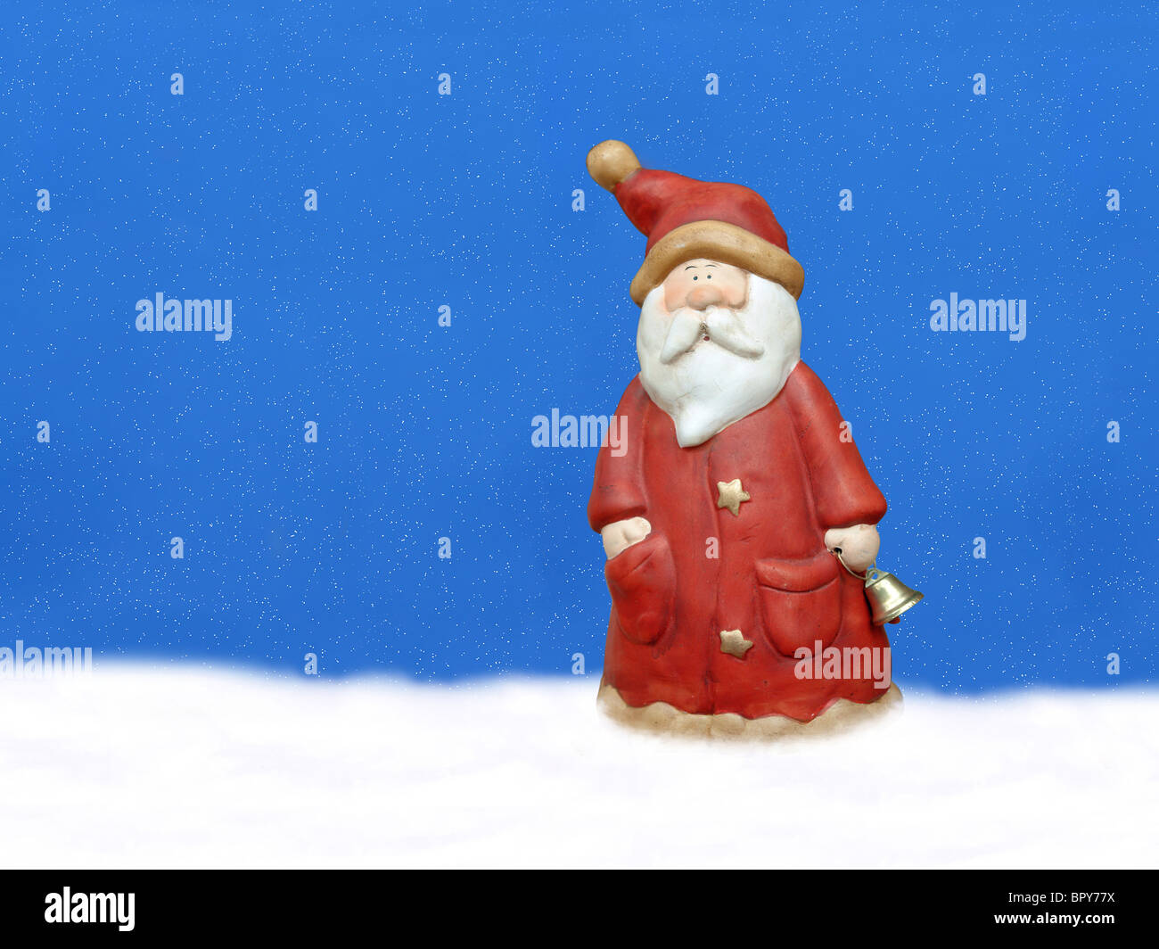 Santa clause with golden bell standing on snow against snowing sky ...