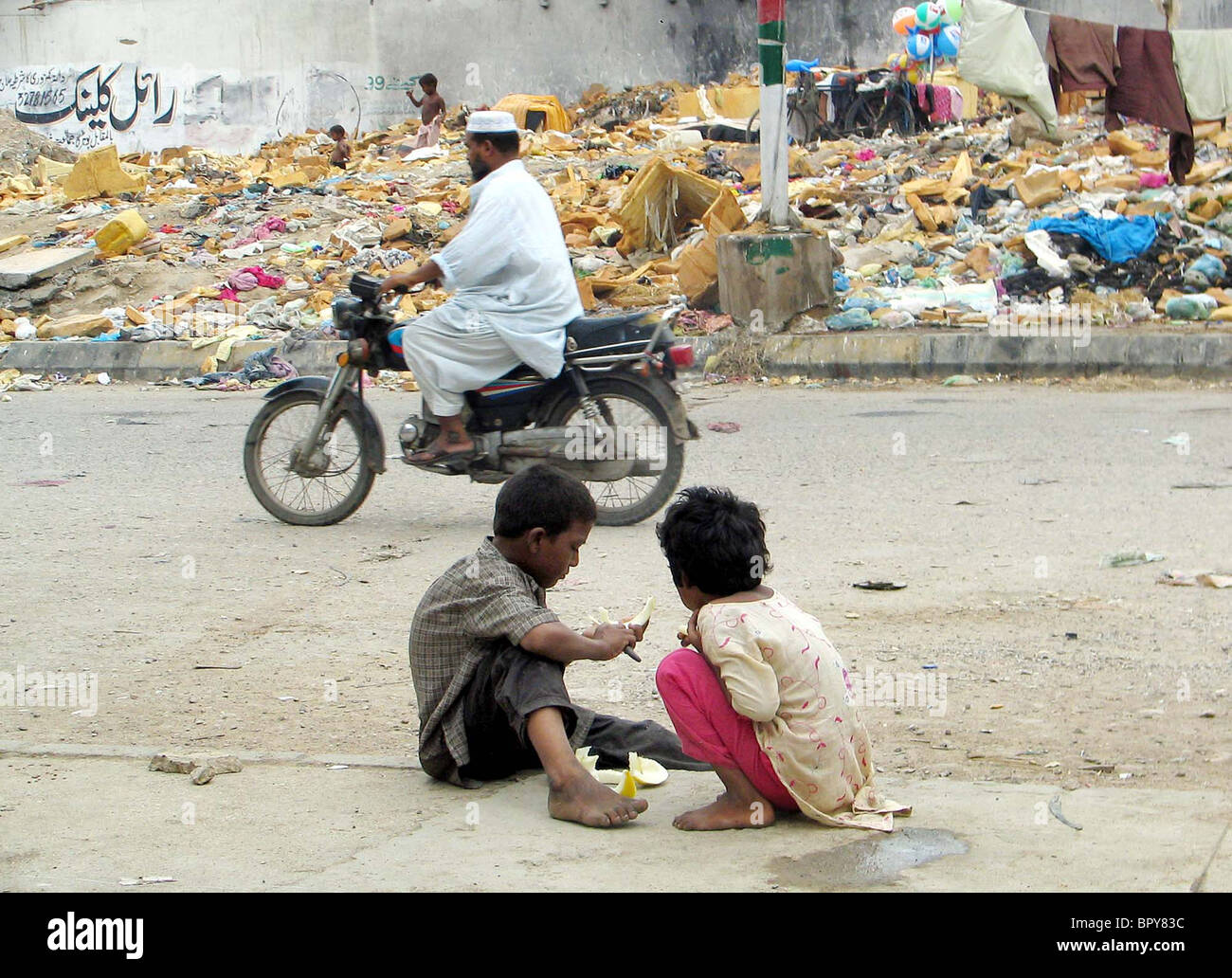 Two children eat fruit after get it from heap of garbage that lays down ...