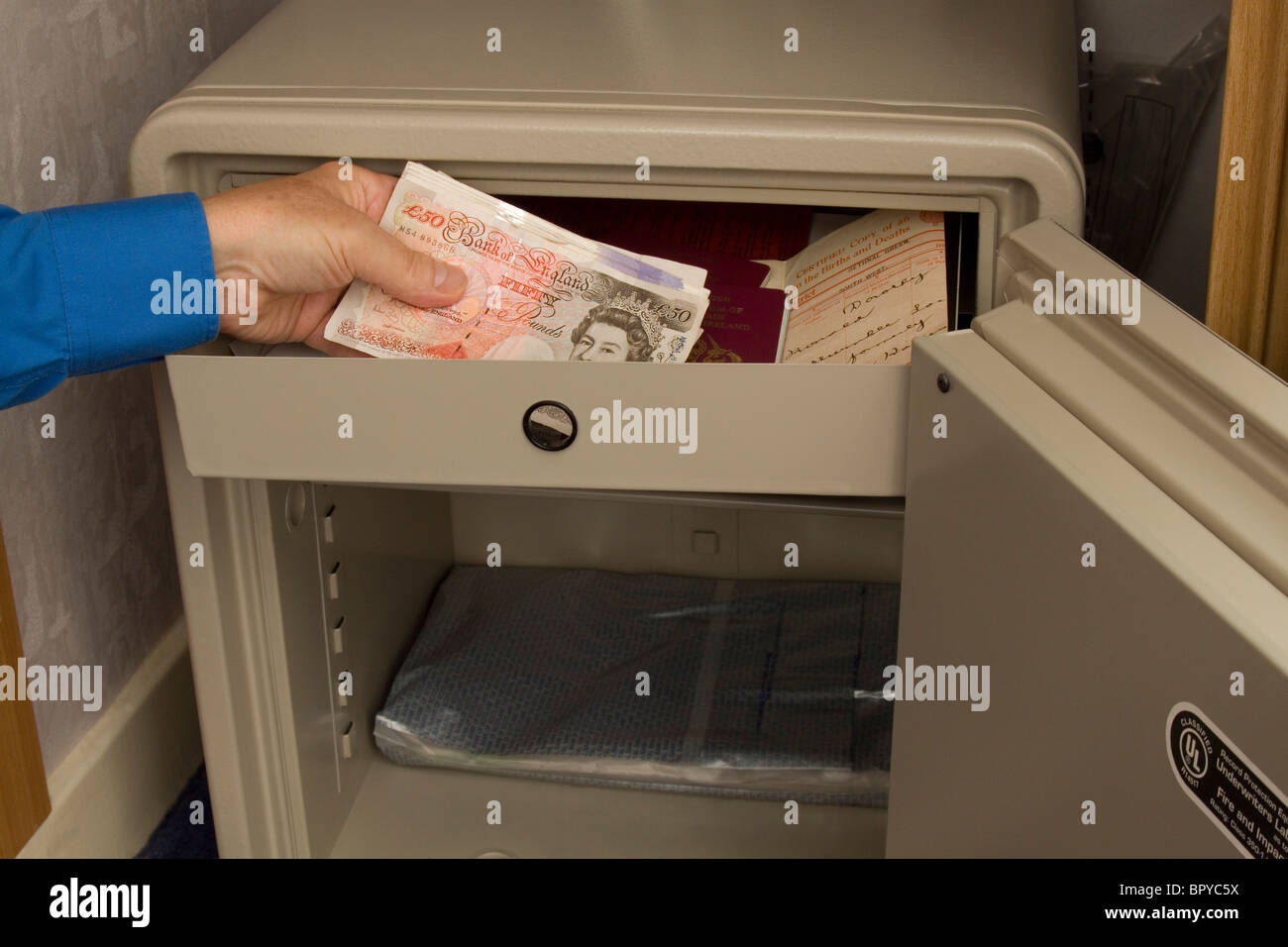 A mans hand seen taking money from a home safe Stock Photo - Alamy