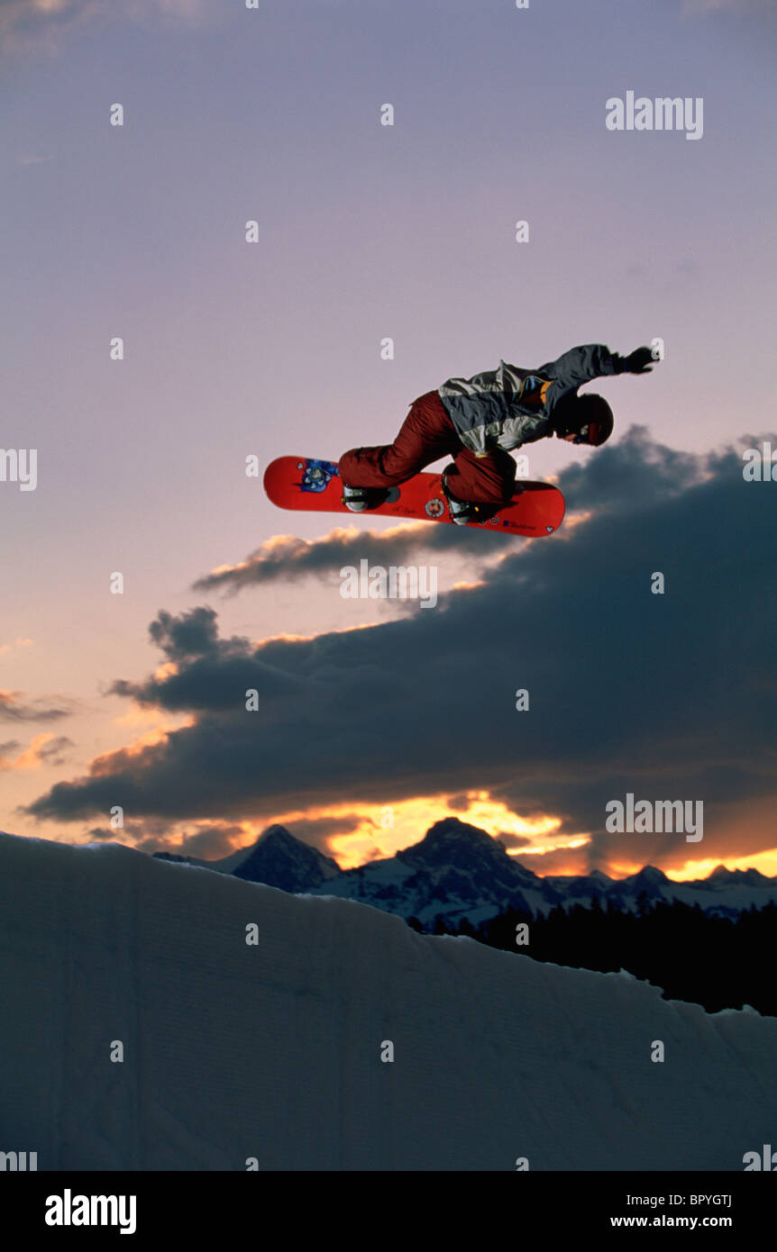 Snowboarder performs an air at sunset Stock Photo - Alamy