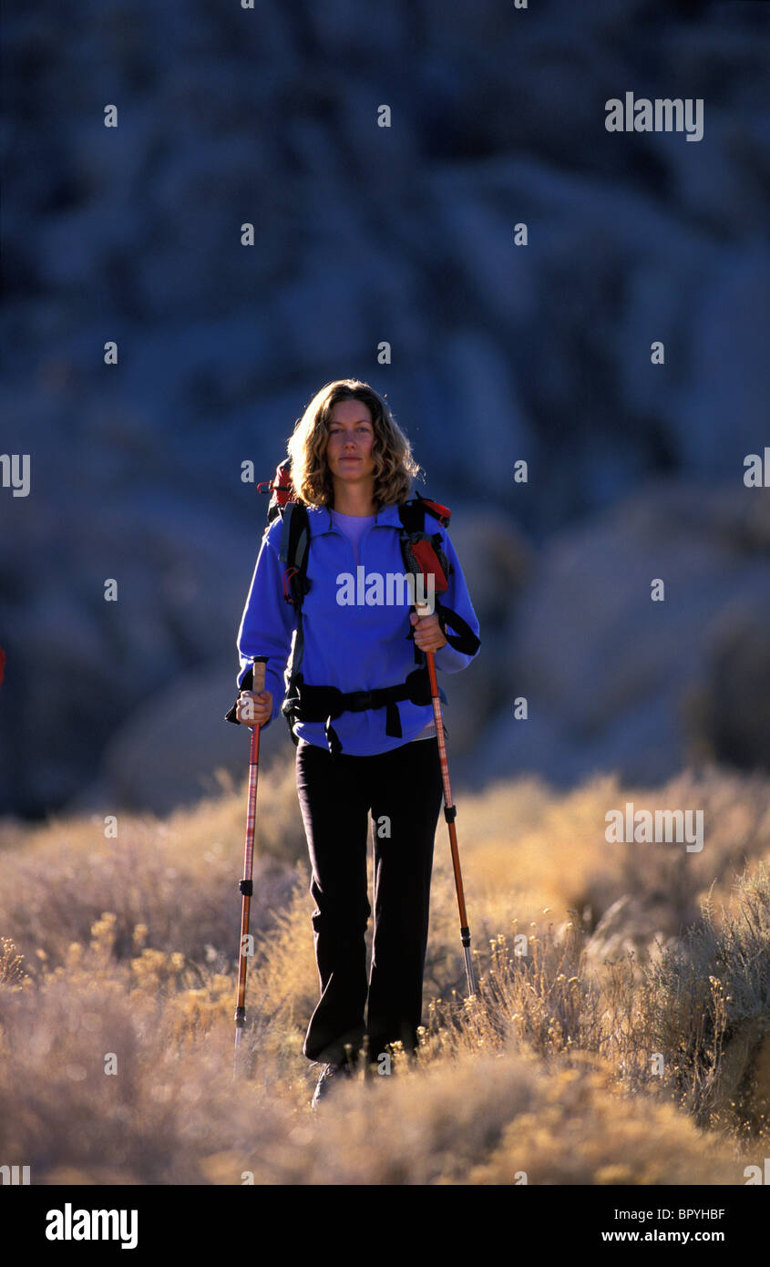 An athletic woman goes hiking / trekking / walking through the desert ...