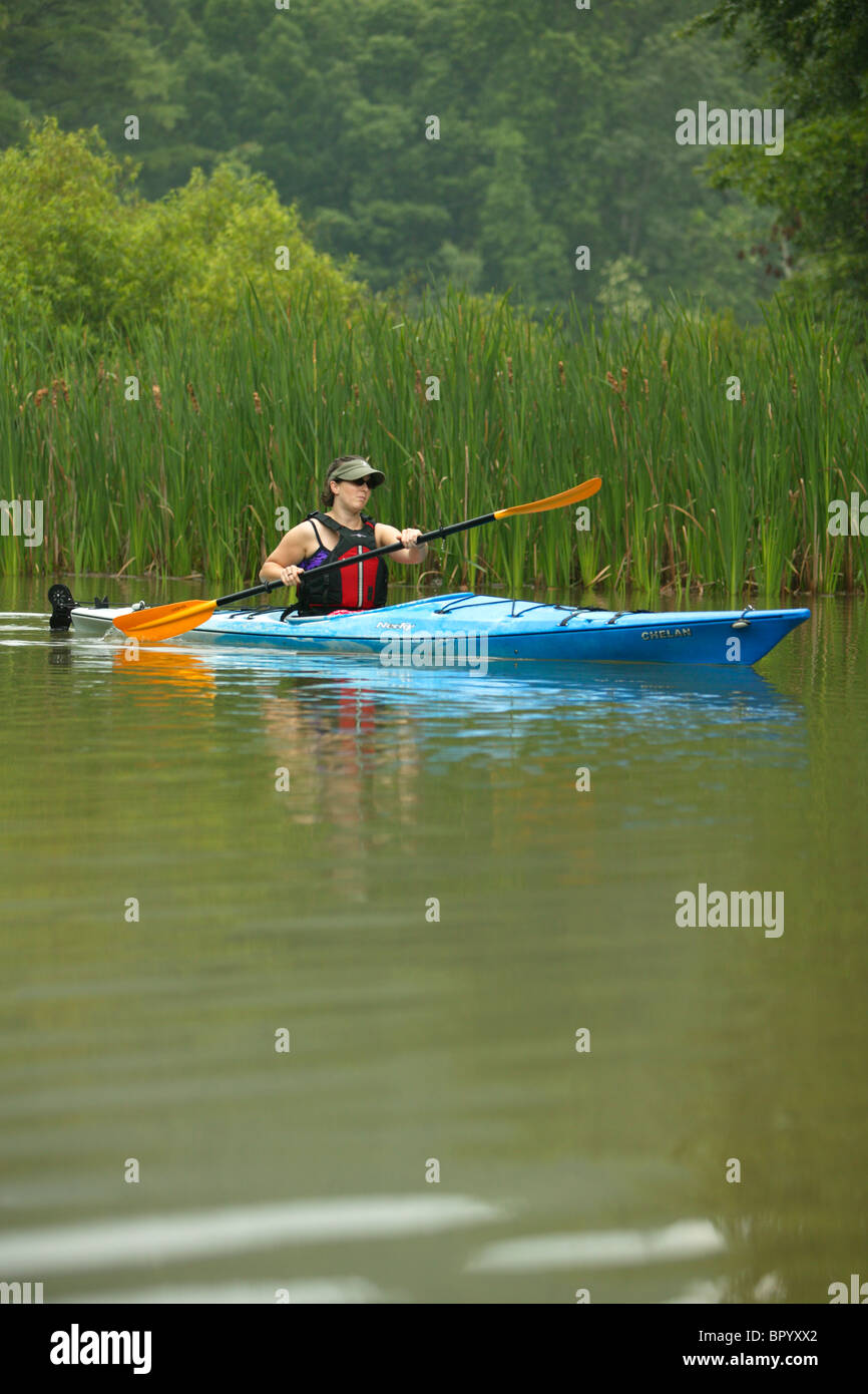 Female kayaker paddles out from the reeds on Lake Summit near Tuxedo ...
