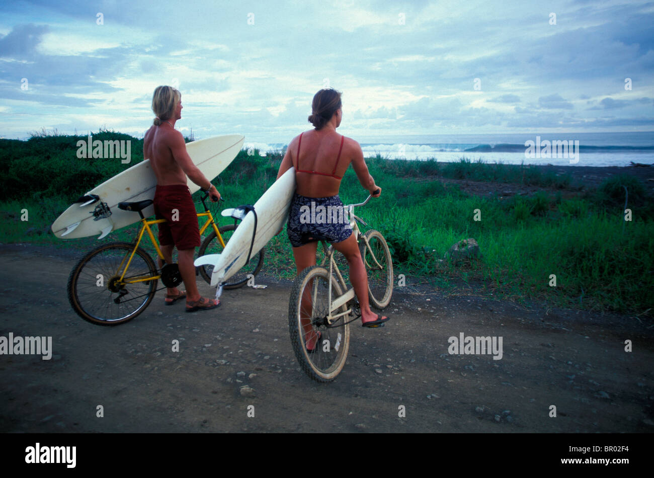 Two people watching the surf on cruiser bikes Stock Photo - Alamy