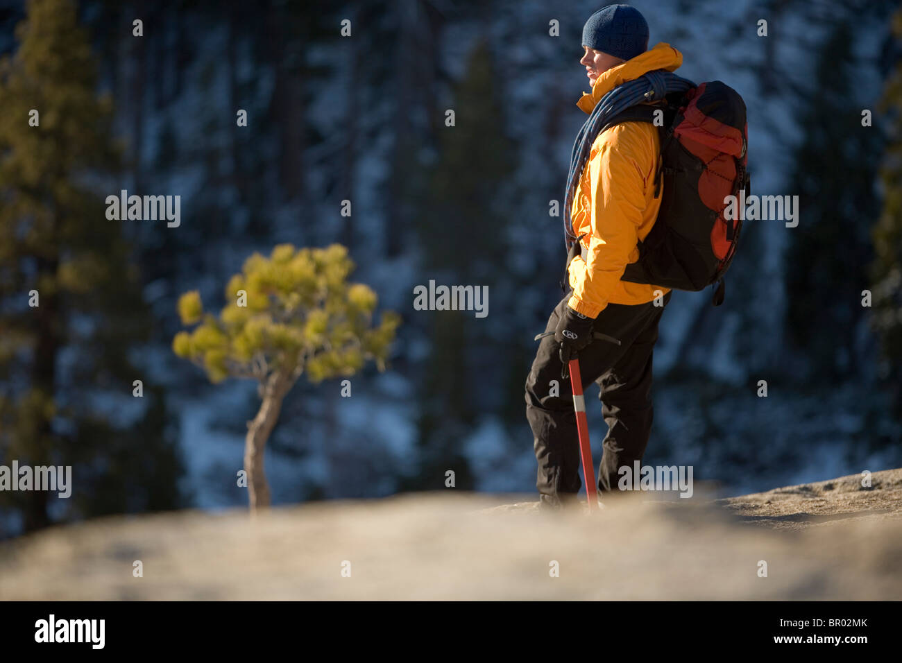 A man hikes along a ridge carrying his ice axe while backpacking in the ...