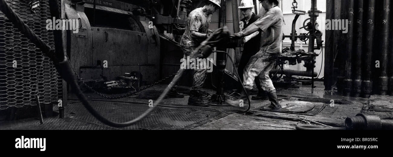 Three men work on an oil rig adjusting equipment Stock Photo - Alamy