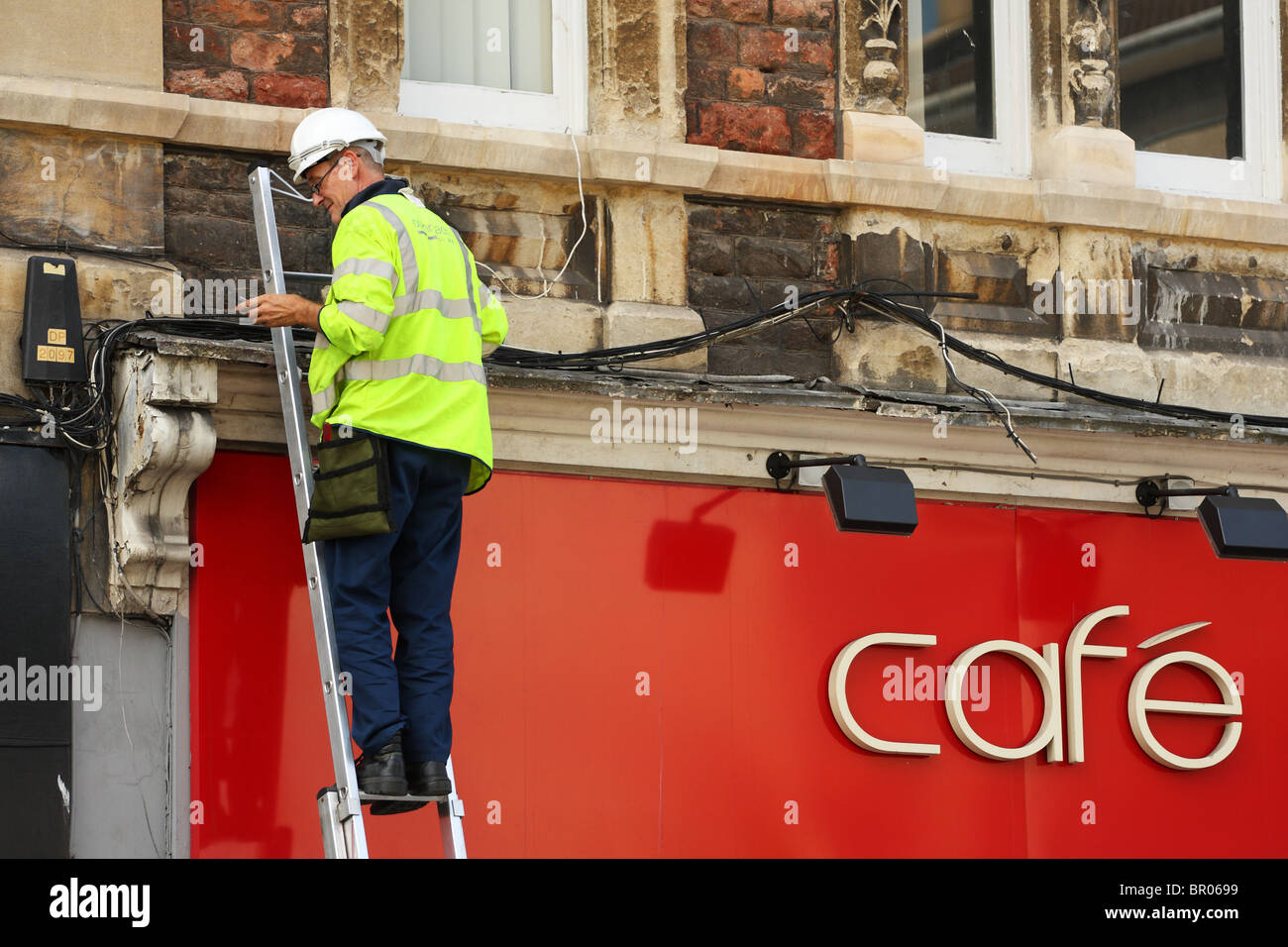 Workman on ladder using mobile phone Stock Photo - Alamy