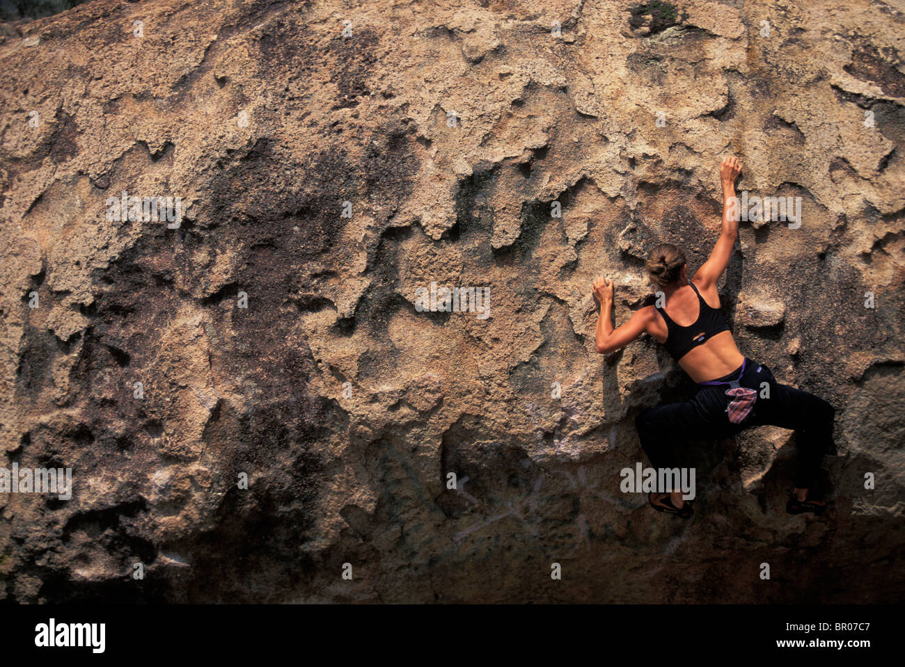 A female rock climber boulders on a bouldering route in a remote ...