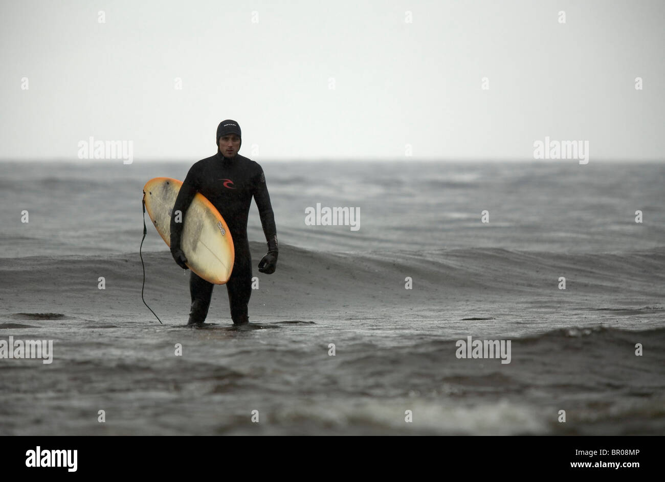 A man stands in knee deep water after facing the harsh canadian surf ...