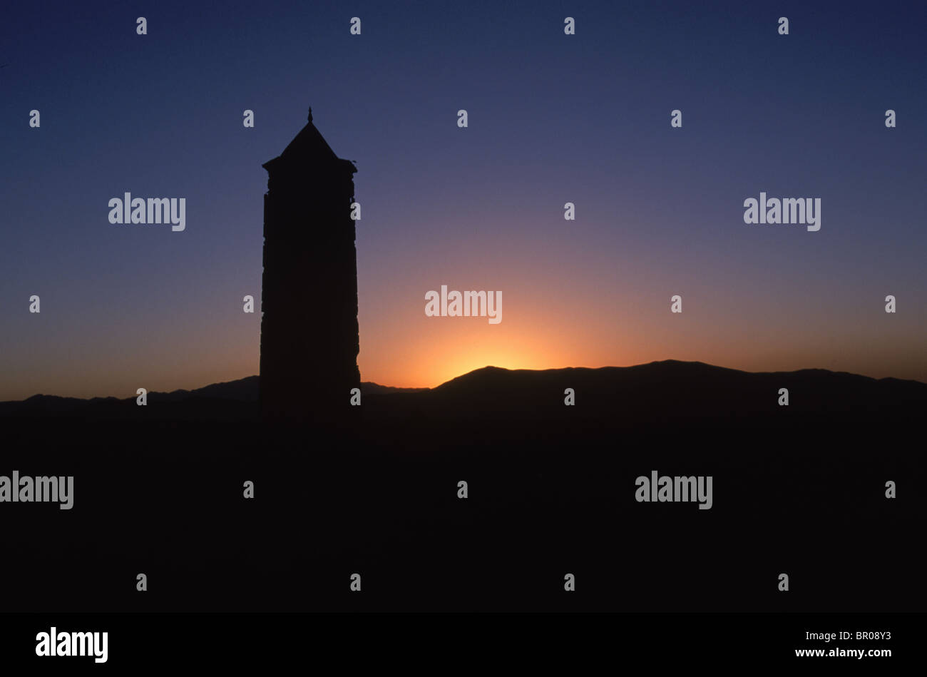 Dawn light silhouettes a slender brick minaret outside of Ghazni ...