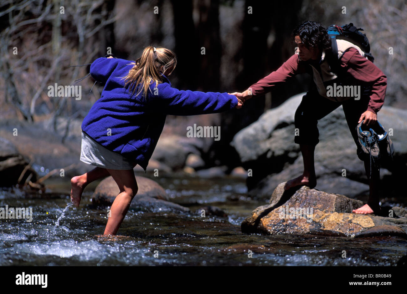 A man helps a woman cross a stream Stock Photo - Alamy