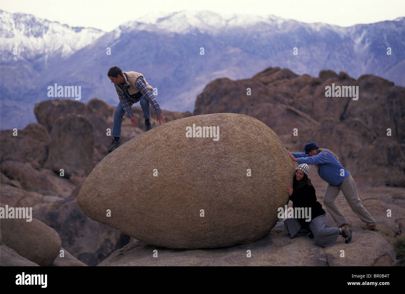 Two women trying to tip over a huge boulder Stock Photo - Alamy