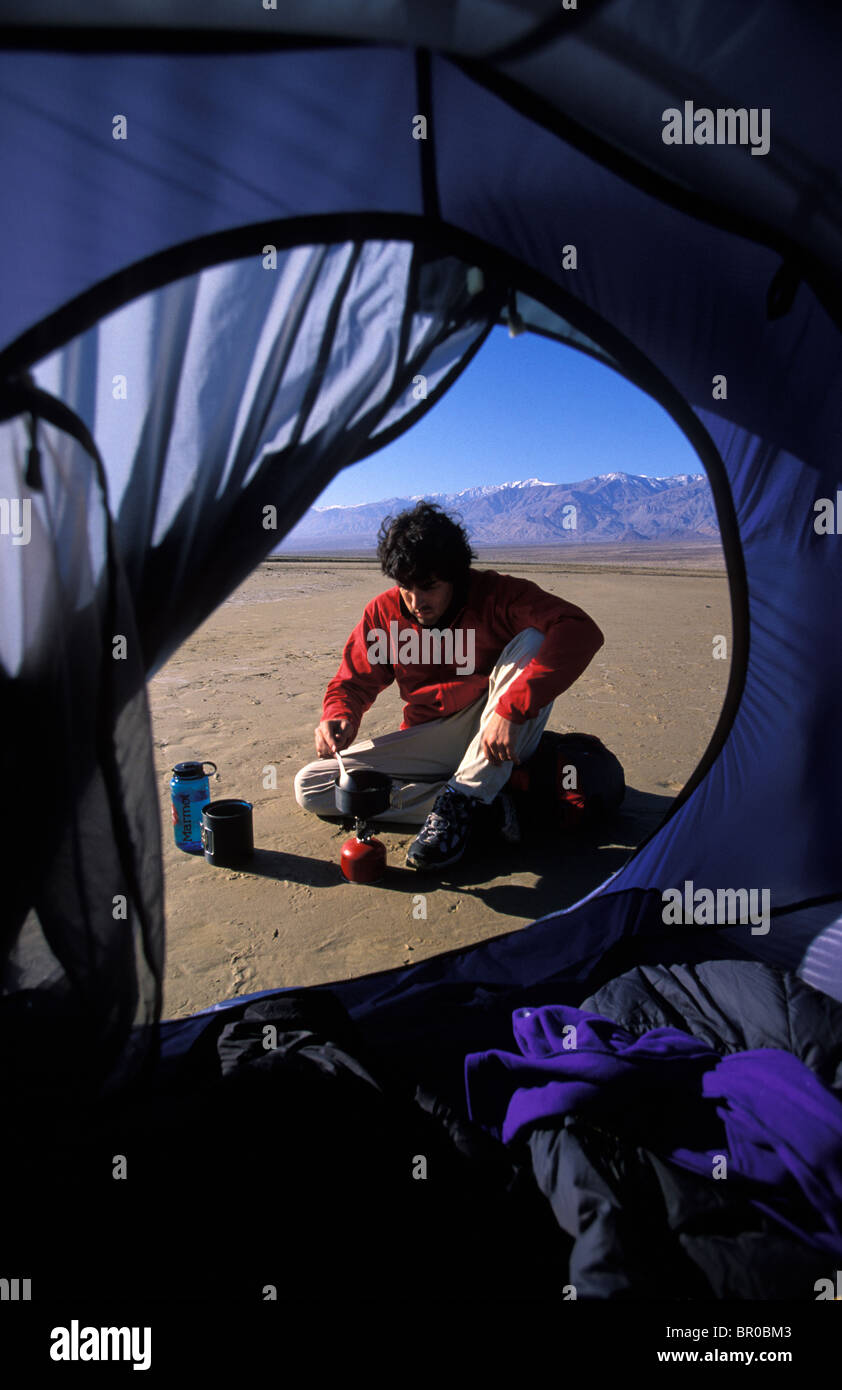A man cooking on a camp stove outside of his tent in the desert Stock ...