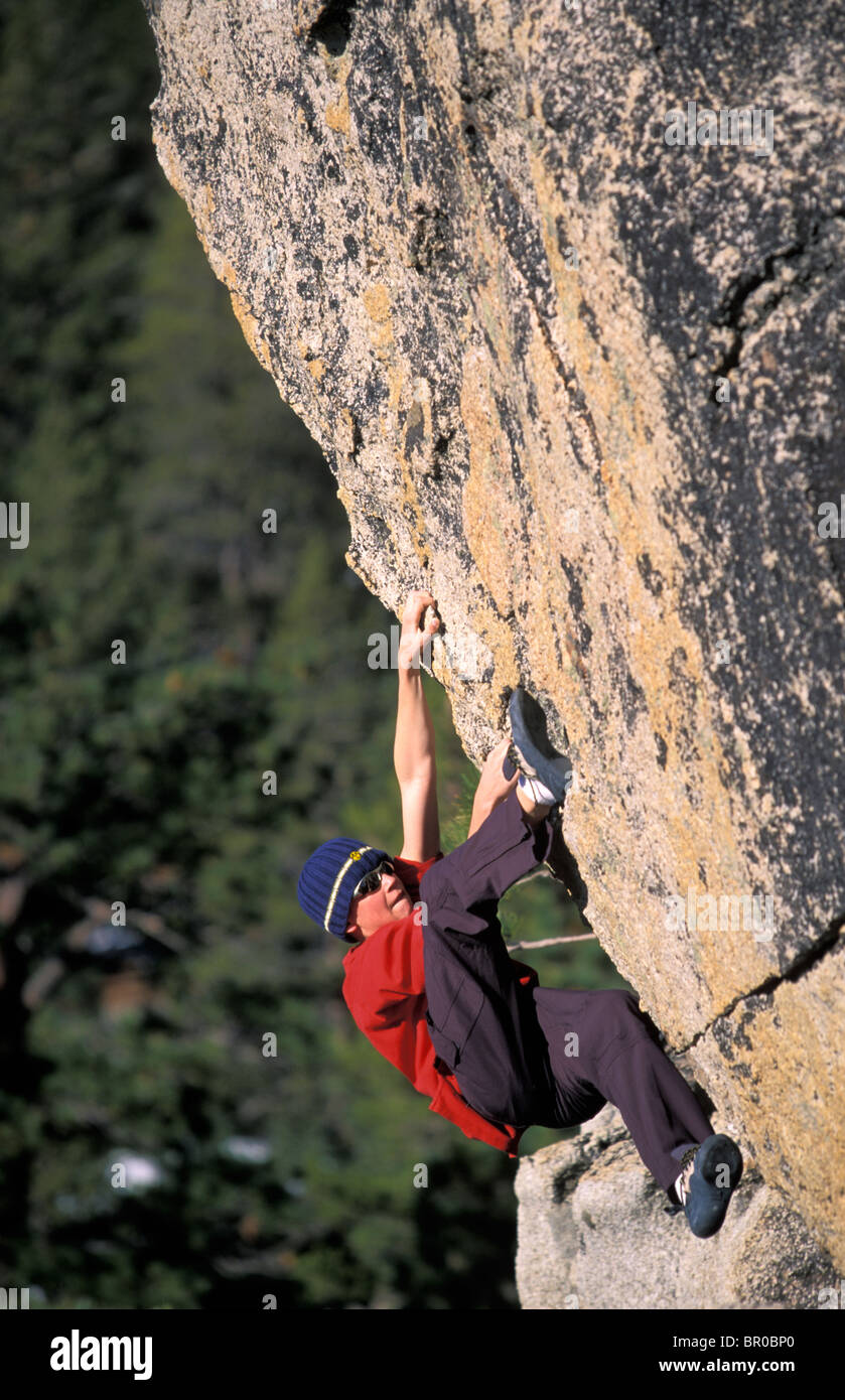 A young male rock climber bouldering on granite above a forest Stock ...
