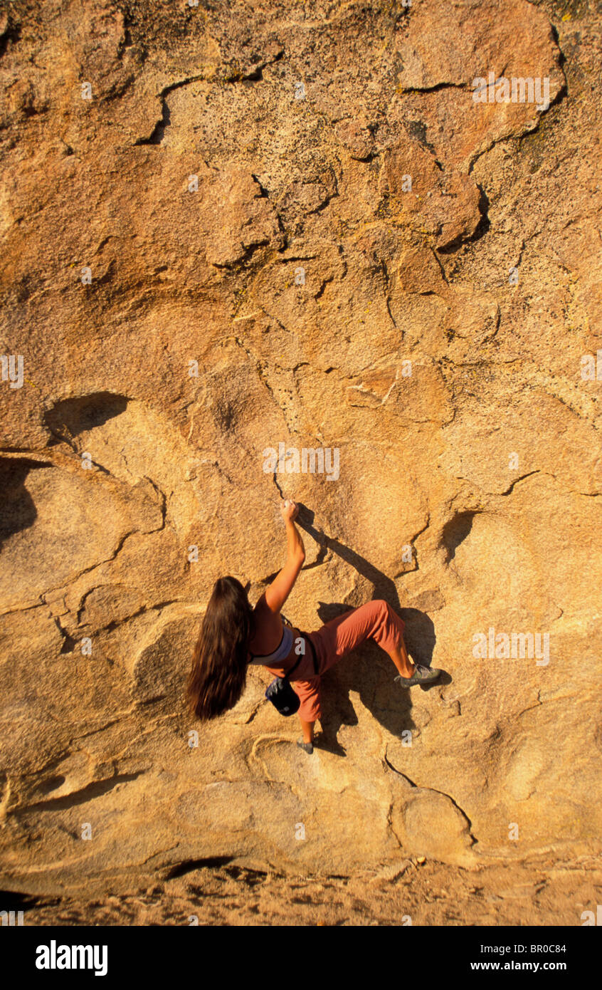 A female rock climber bouldering on an overhanging bouldering route in ...