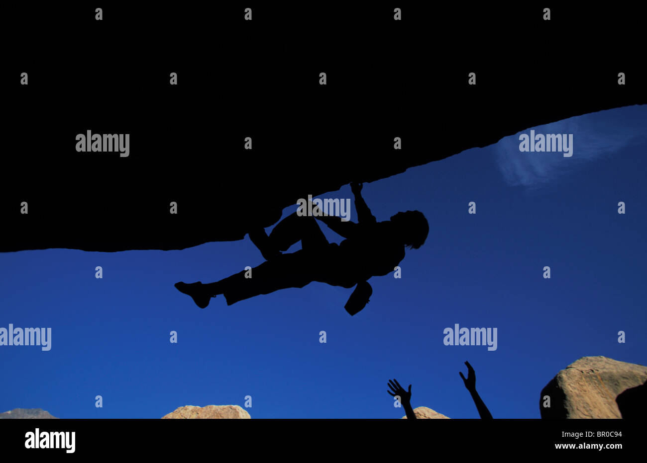 A male rock climber hanging upside down on an overhanging bouldering ...