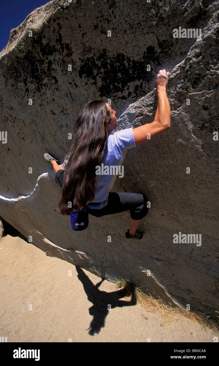 A female rock climber crimping while climbing a ledge on a bouldering ...
