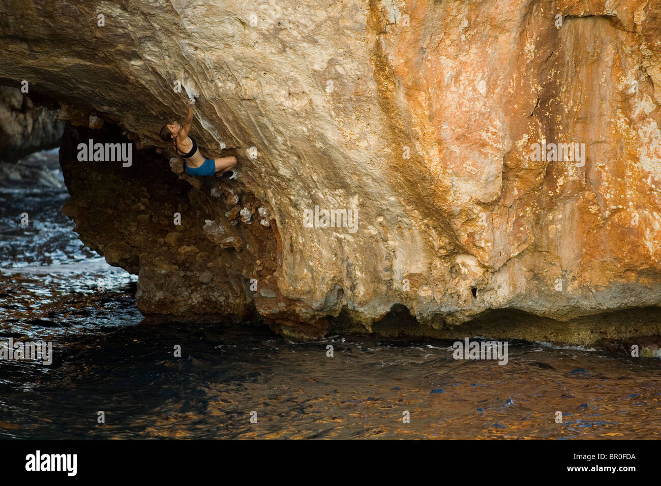 A female rock climber rock climbing / deep water soloing Stock Photo ...