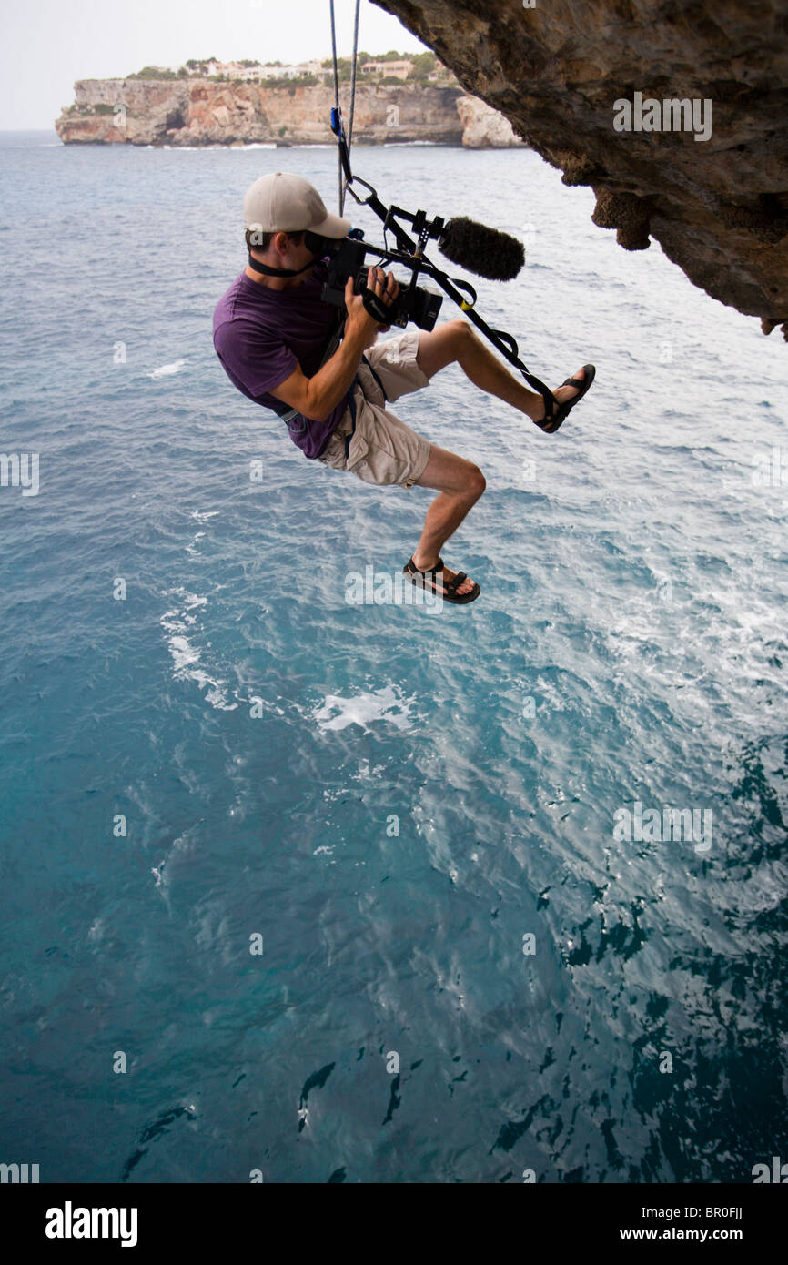 A man hanging on a rope above the ocean and filming video Stock Photo ...