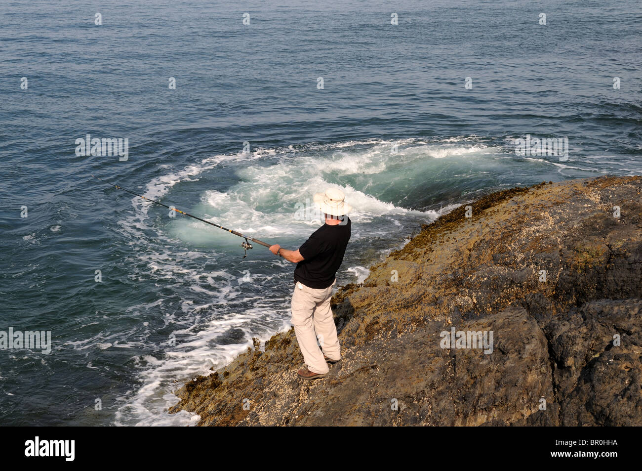 Man fishing off rocks near Mwnt Cardigan Bay Coastal Path Ceredigion ...