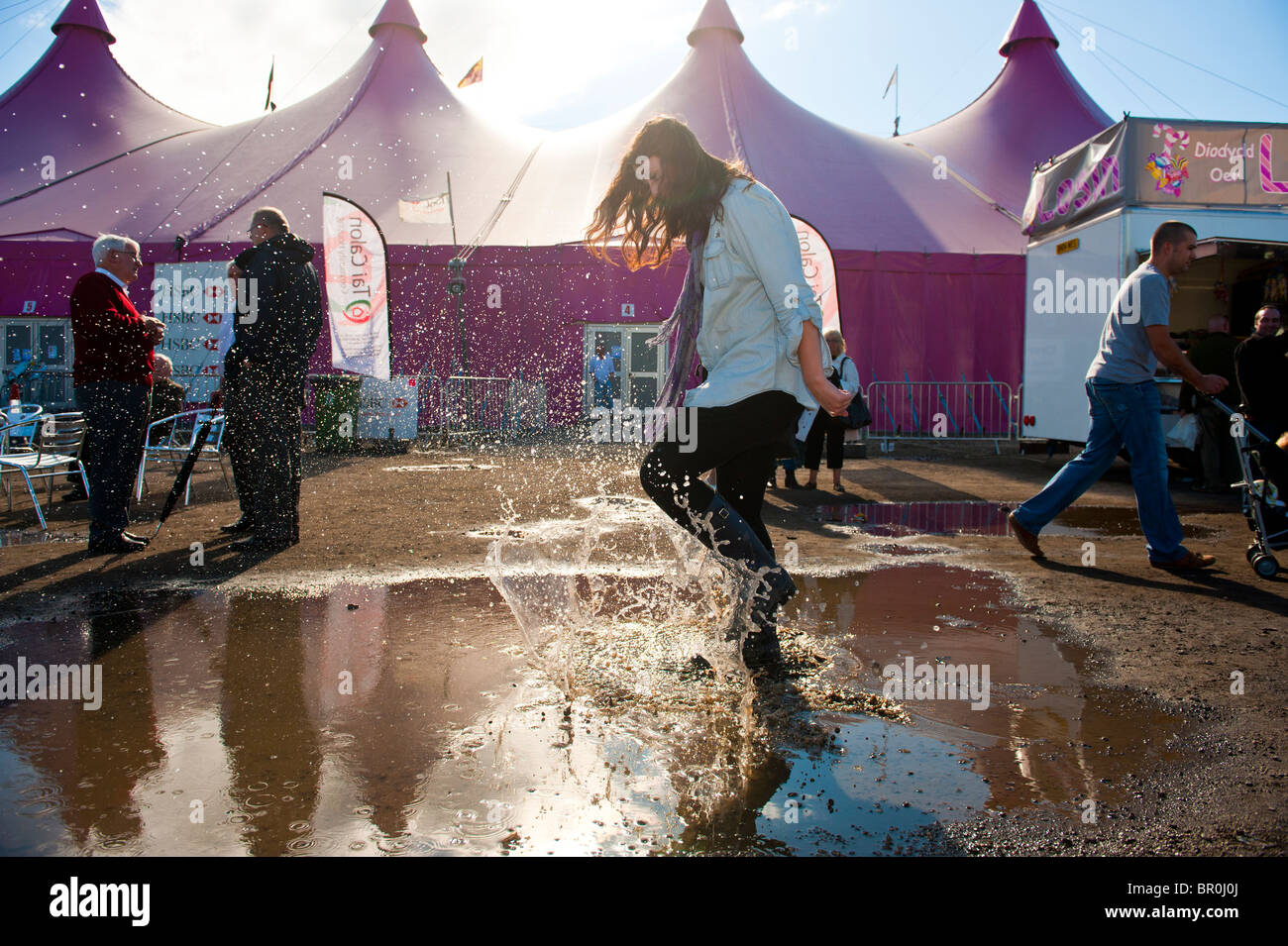 A woman splashing in a puddle of rainwater at the National Eisteddfod ...