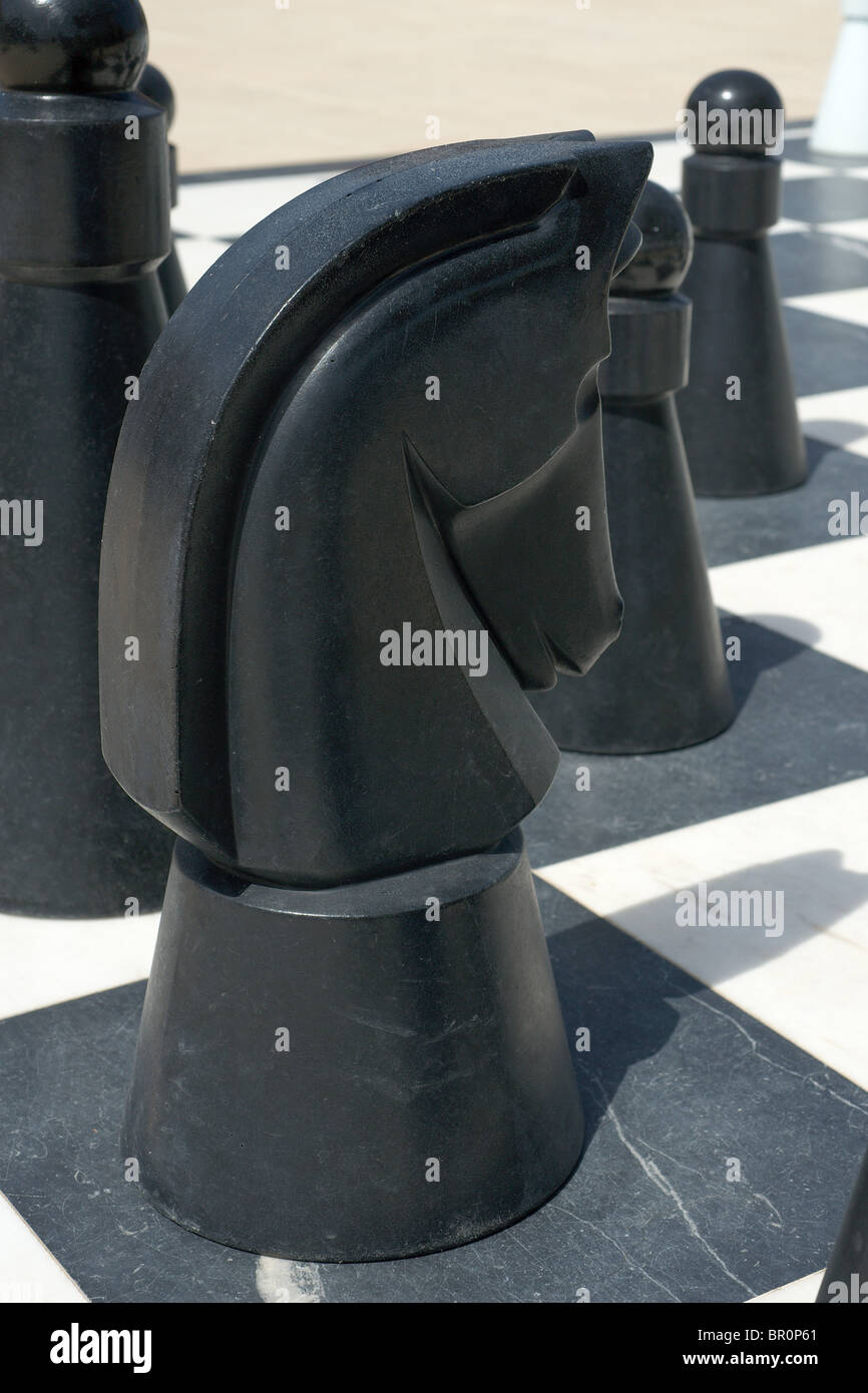 Giant sized black night chess piece on stone board Stock Photo - Alamy
