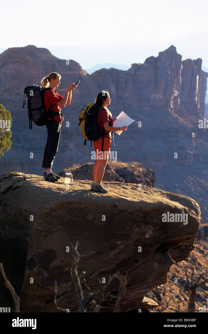 Two women standing on rock reading map and compass, Long Canyon, Utah ...