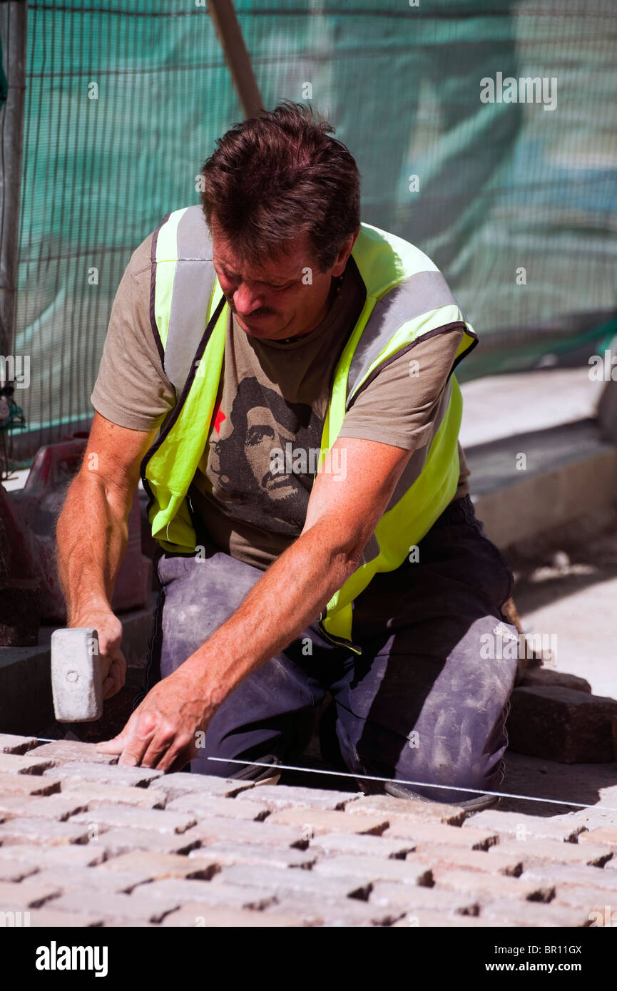 Man at work laying cobblestone setts in new paving scheme, Hereford, UK ...