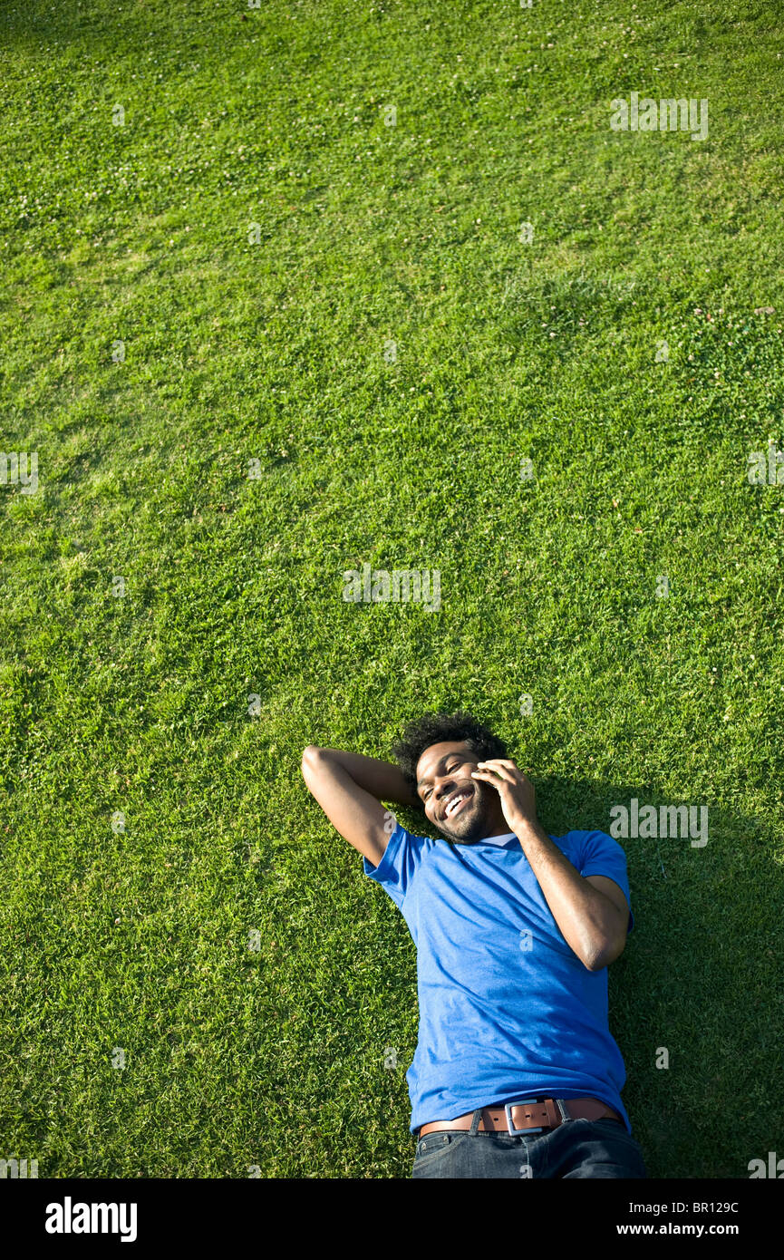 African American man using cell phone laying on grass Stock Photo - Alamy