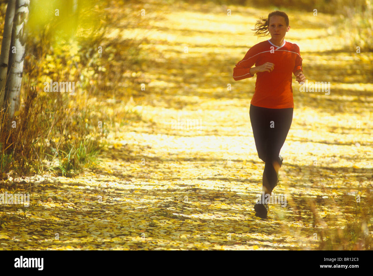 Female running on leaf laiden road during the autumn season in ...