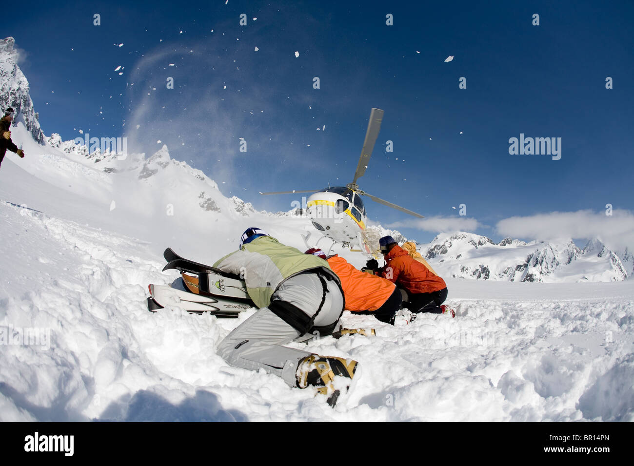 Skiers prepare to load helicopter while skiing in backcountry of ...