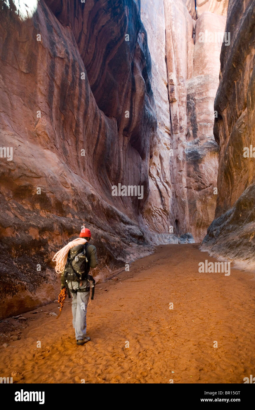 A man hiking with rope over shoulder in canyon, Arches National Park ...