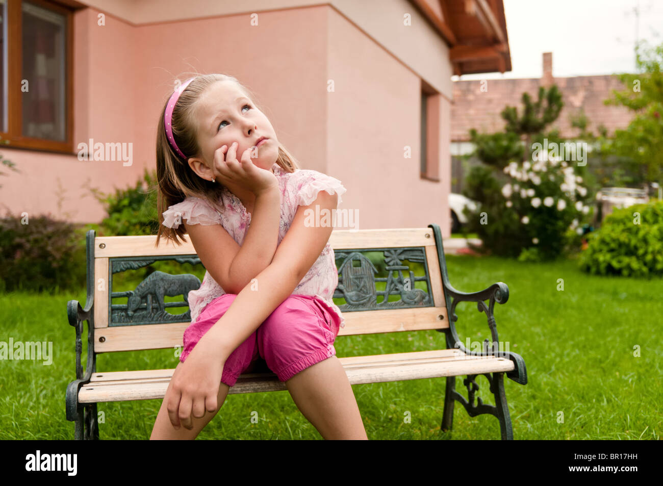 Girl dreaming - child sitting on bench in garden Stock Photo - Alamy