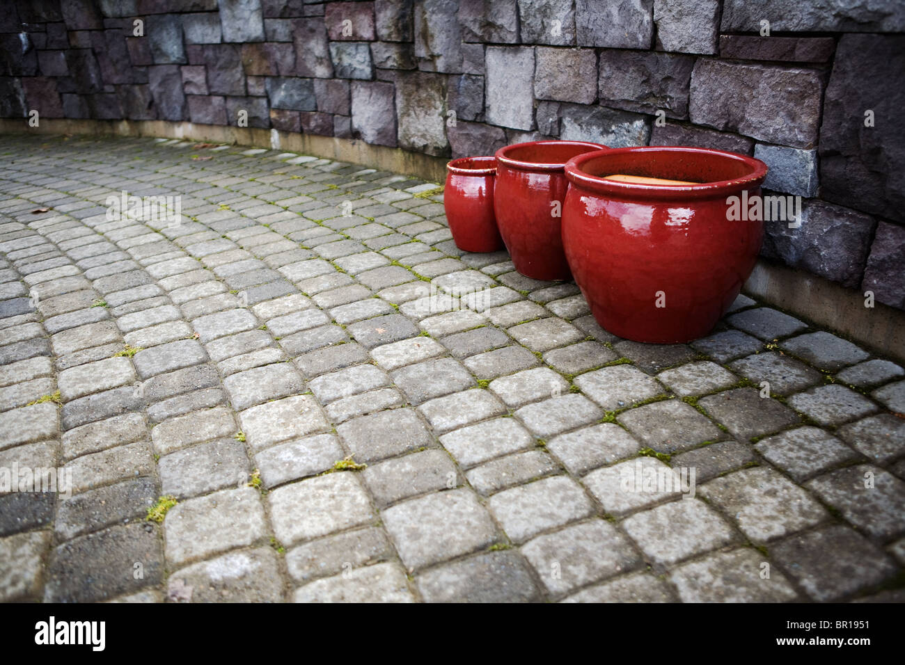 Wide view of three empty flower pots on cobblestone path along a ...