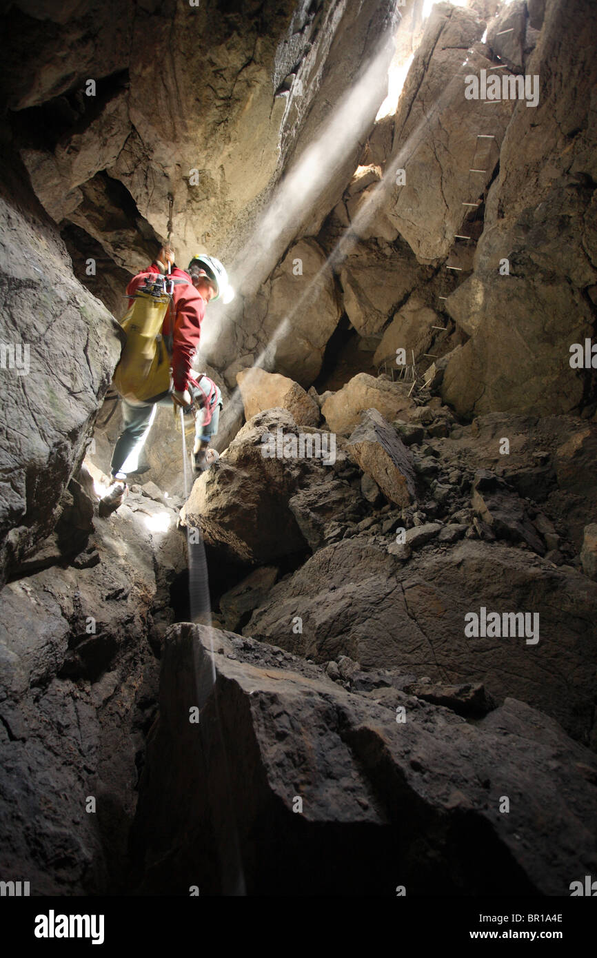 A cave explorer descends into a daylight lit underground chamber in the ...