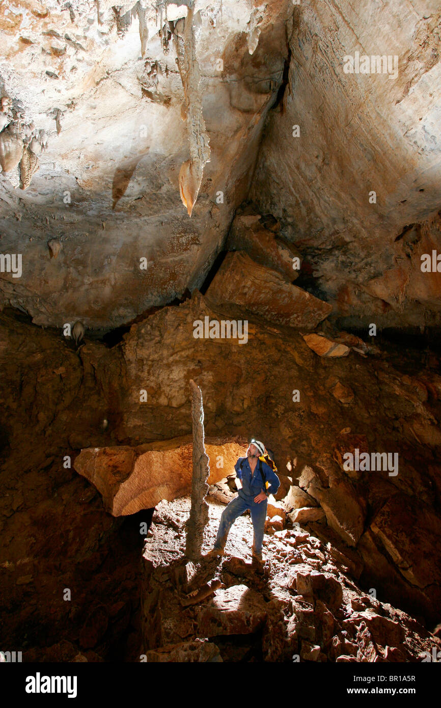 Cave explorer in a blue suit admires formations underground in a cave ...
