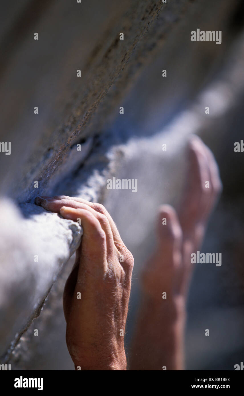 Close up of a climber's hands holding onto and reaching for a small ...