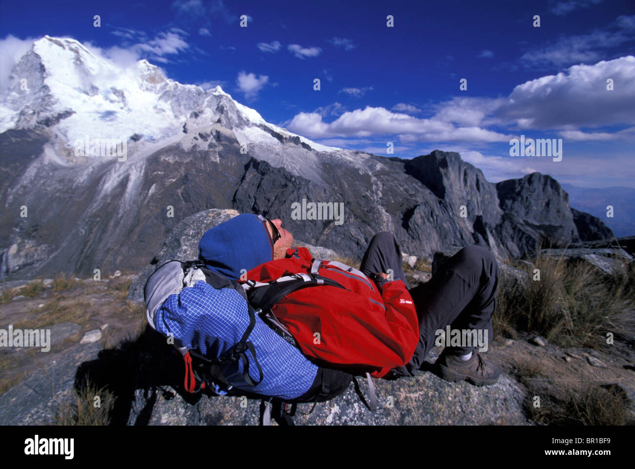 A man laying on his backpack with a scenic view in Cordillera Blanca ...