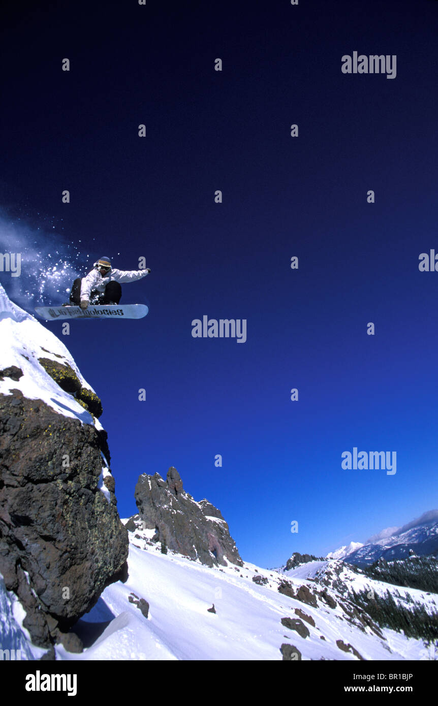A snowboarder launching off a cliff and grabbing his board near Lake ...