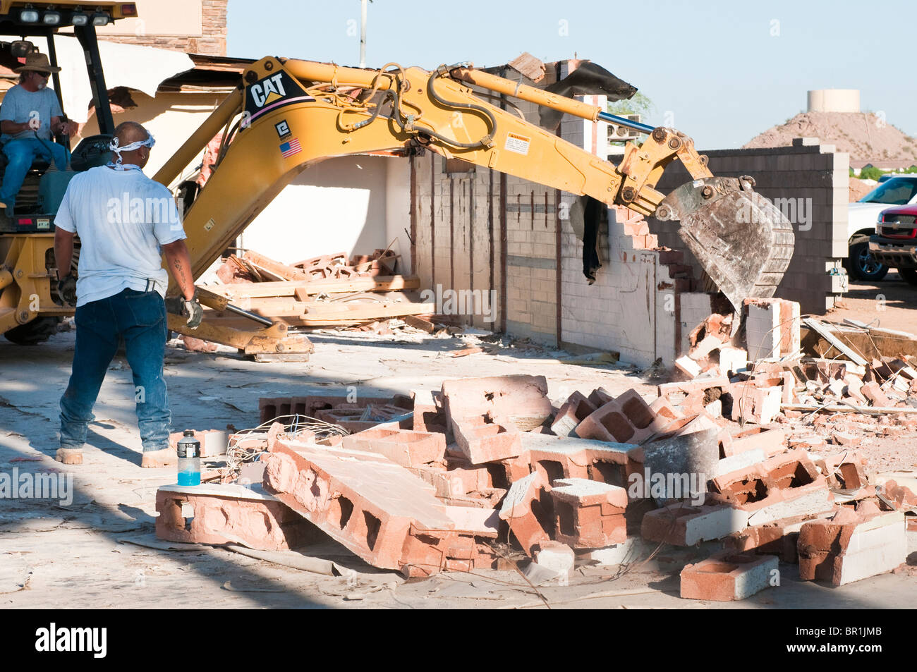 A backhoe is being used to knock down an old commercial building and ...