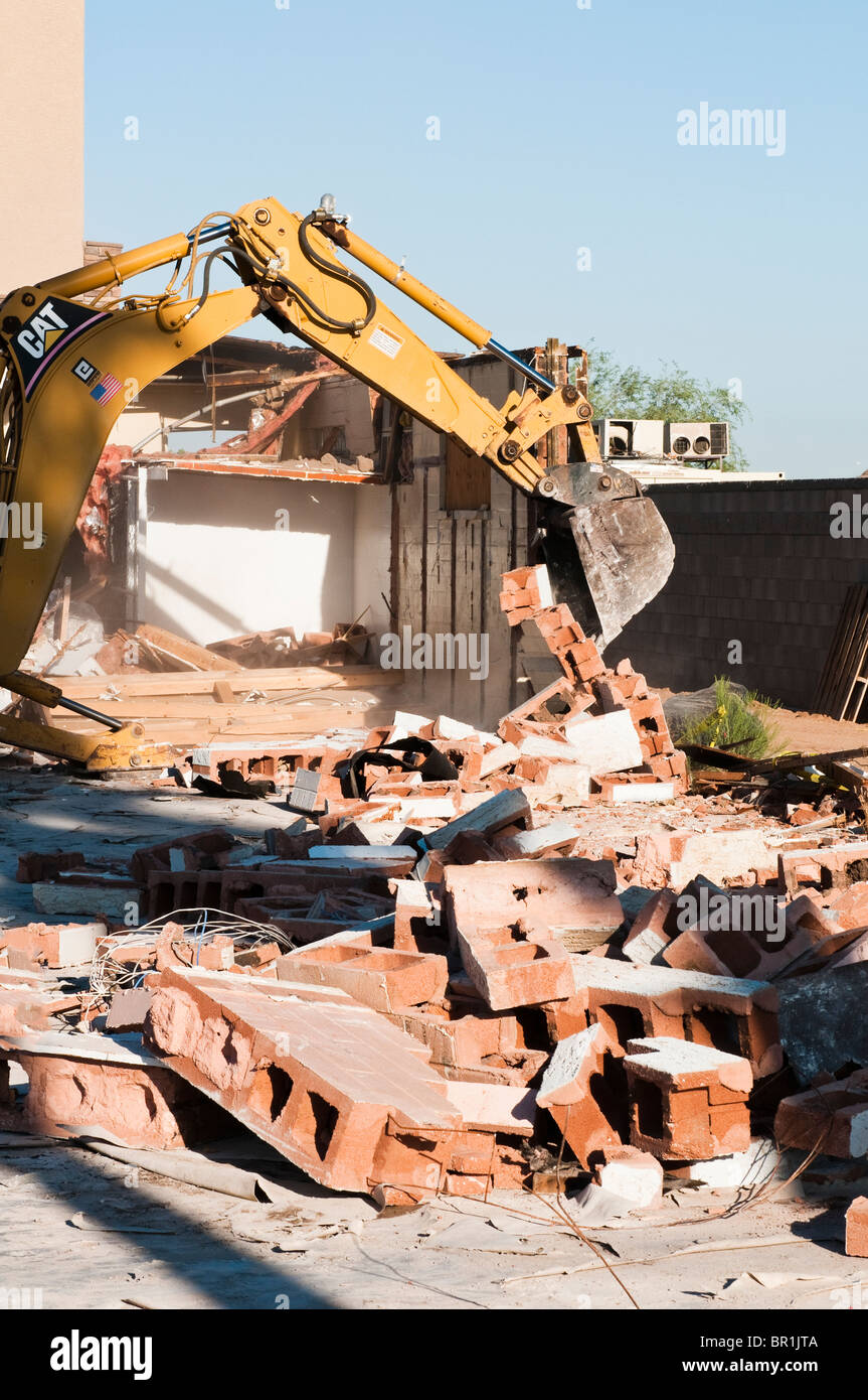 A backhoe is being used to knock down an old commercial building and ...