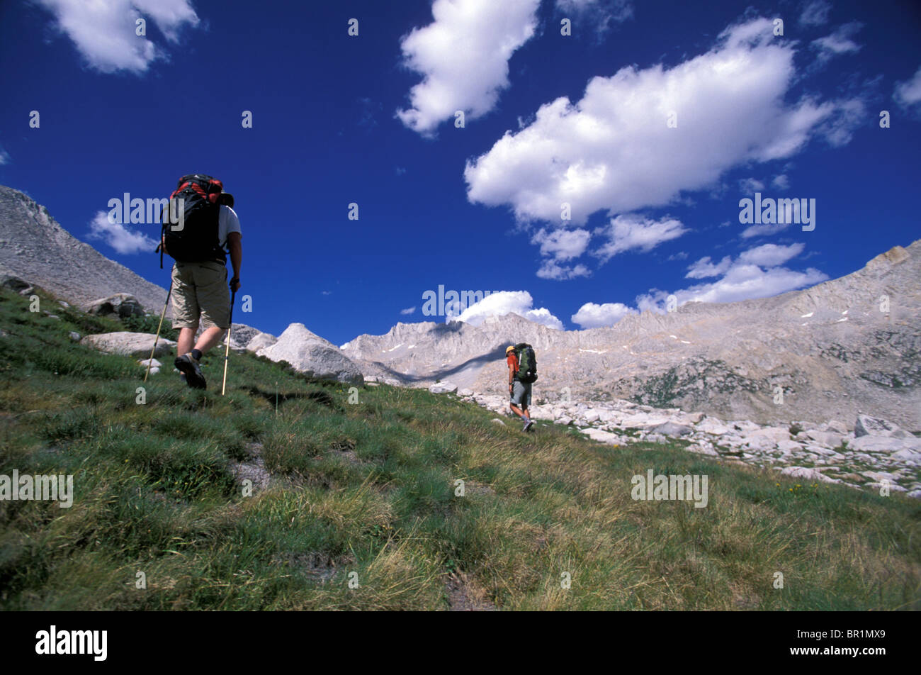 Two backpackers hiking up a slope in eastern Sierra Nevada mountains ...