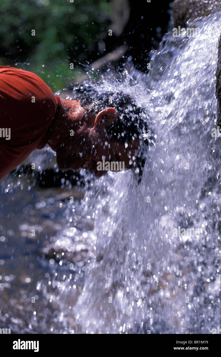 Man washing his face in a waterfall in eastern Sierra Nevada mountains ...