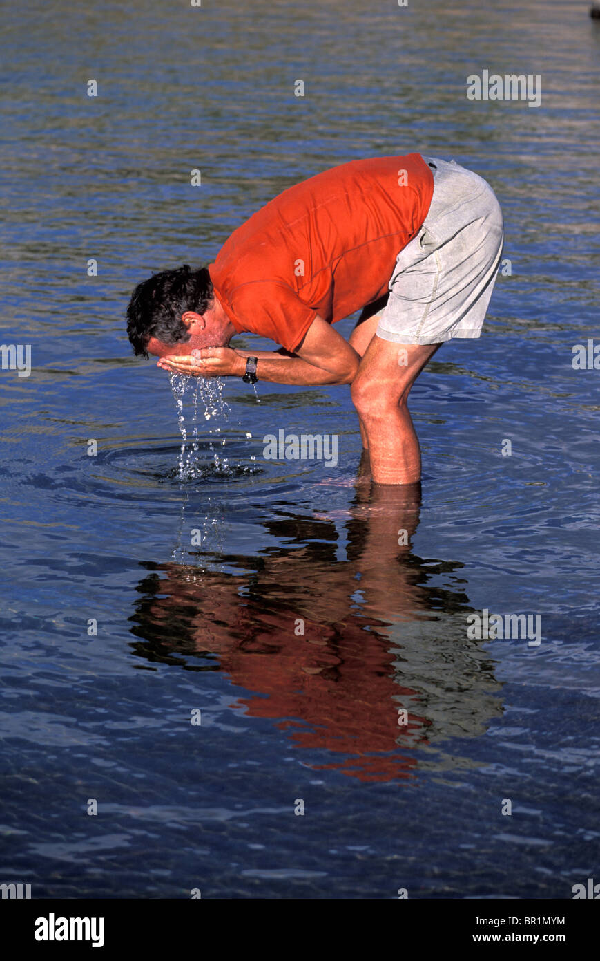 Man washing his face in a mountain lake in eastern Sierra Nevada ...