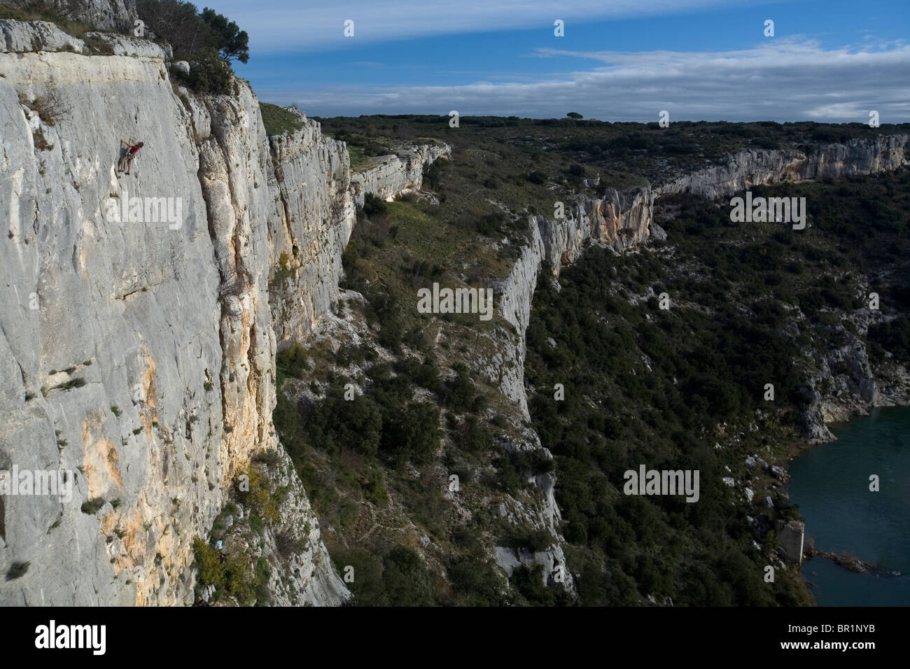 Man with a red t-shirt climbing on a grey and orange rock cliff with ...
