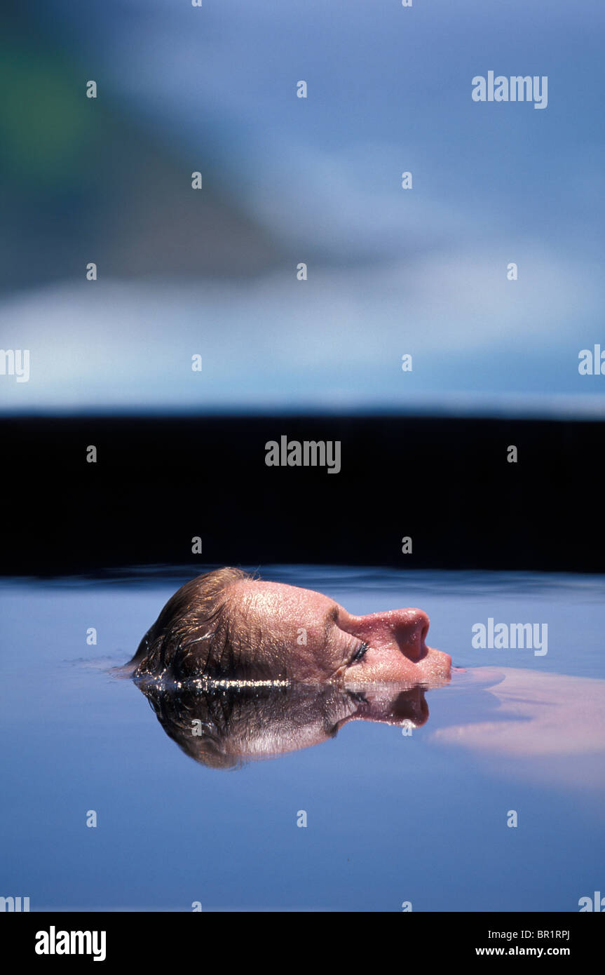 A woman dunking her head under water and reflecting in a hot spring by ...