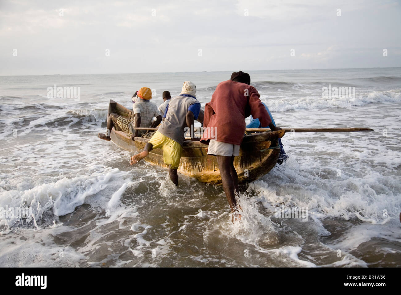 Fishermen pushing a boat into the ocean in Ghana Stock Photo - Alamy