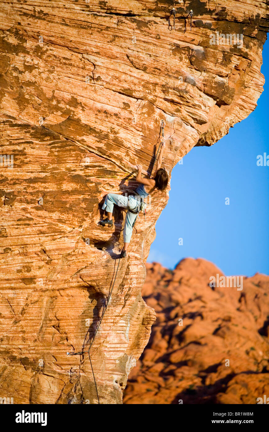 A women stretches to clip the draw on the crux while climbing Stock ...