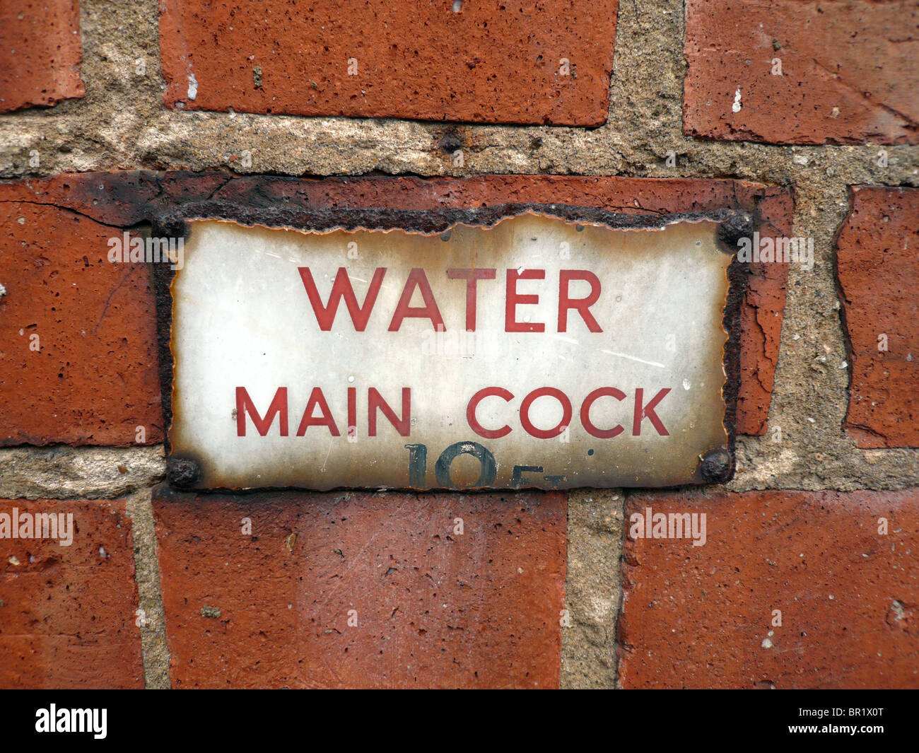 Red brick wall with aged water mains sign that has rusted Stock Photo ...